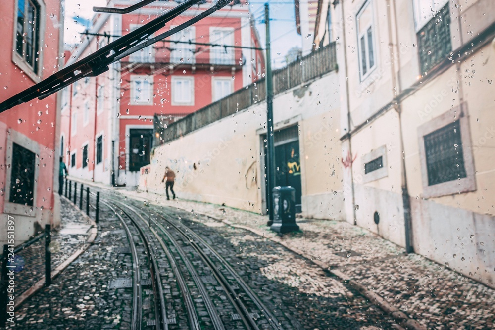 Tramway window view of street with streetcar rails and old houses in ...