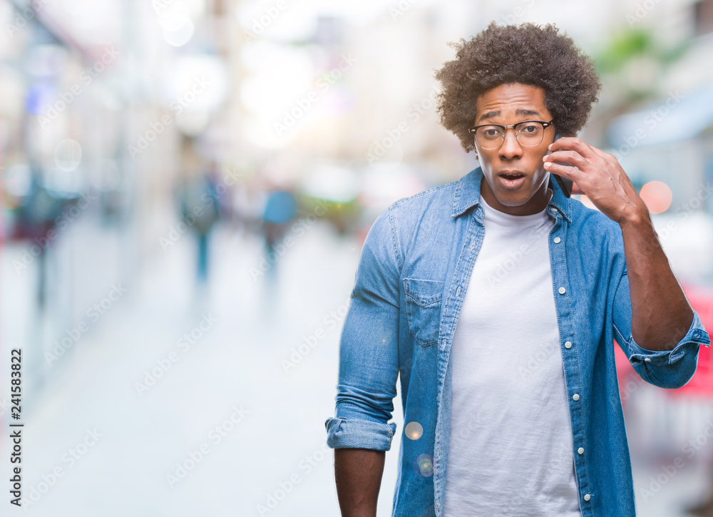 Afro american man talking on the phone over isolated background scared ...