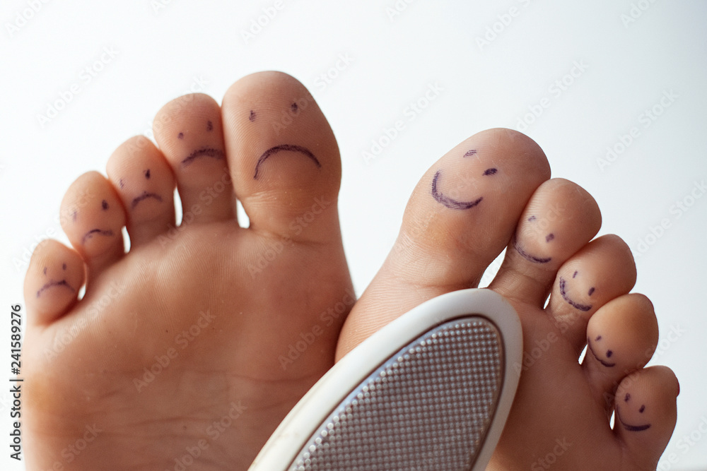 Female toes with painted smileys and a pedicure grater. Foot care ...