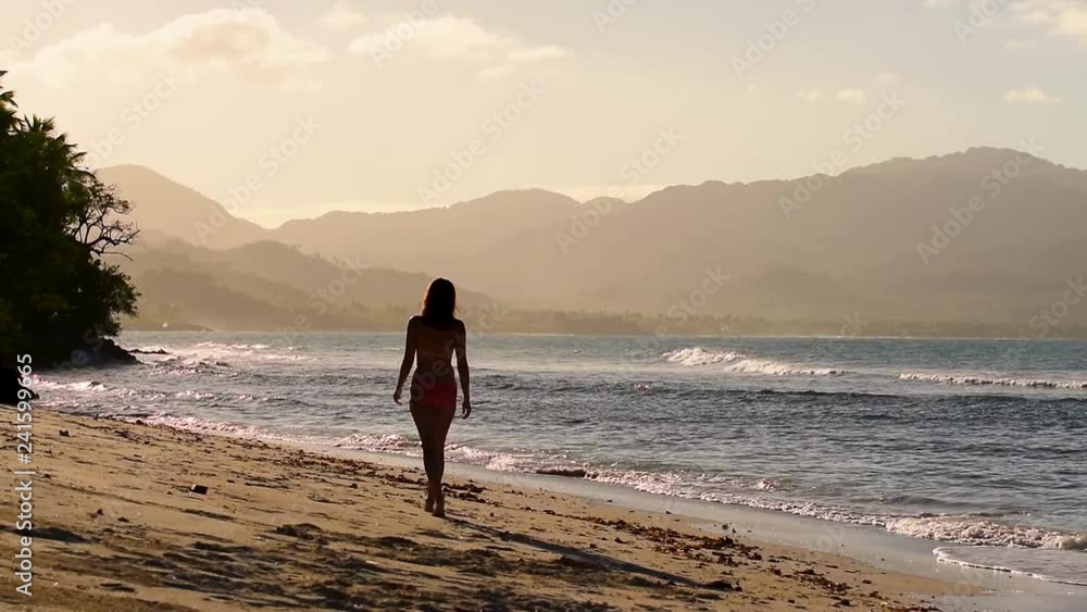 Attractive woman in bikini walk on a beach in sunset. Caribbean paradise in Dominican Republic ...