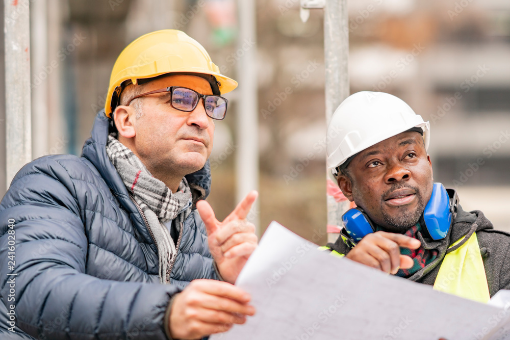 Civil engineers with hardhat and yellow jacket checking technical ...