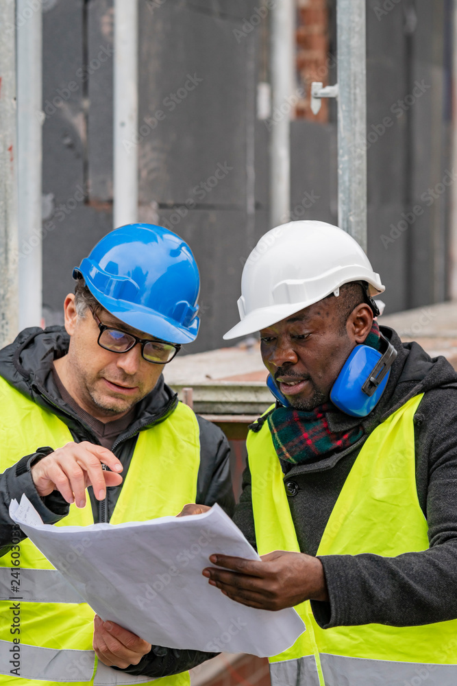 Civil engineers with hardhat and yellow jacket checking technical ...