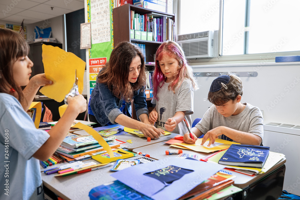 Teacher helping children in a classroom Stock Photo | Adobe Stock