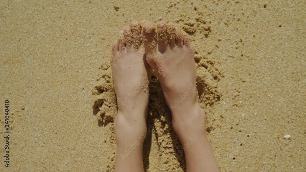 Close up high angle view of feet of barefoot woman on sandy beach ...