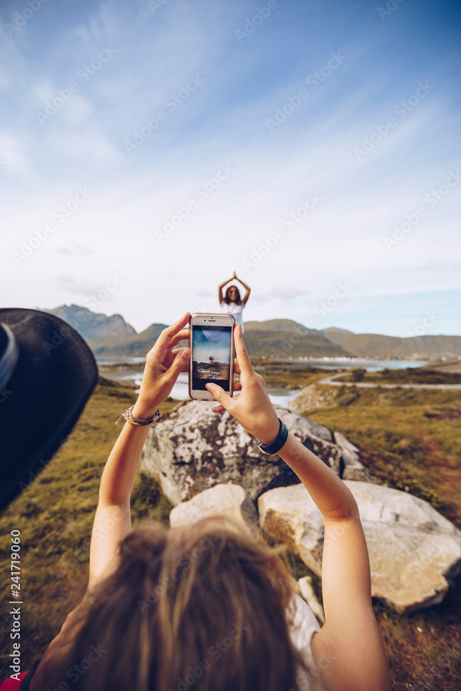 Norway, Lofoten, young woman taking picture of woman in yoga pose Stock ...