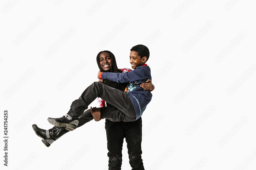 Smiling sister carrying her brother against white background Stock ...
