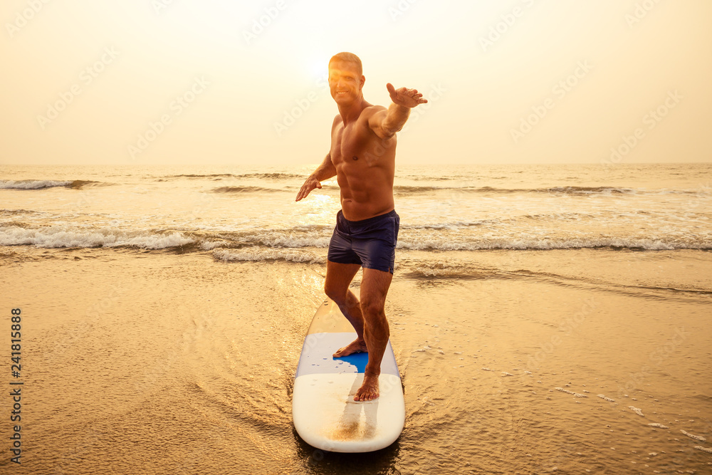 Surfer fitness male with a muscular body with his surfboard at the ...