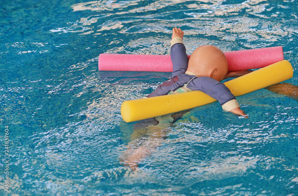 Dummy drowning training baby doll float in the pool with noodles. foto ...