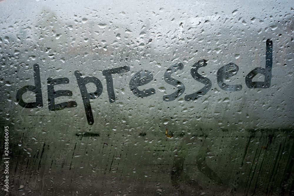 Handwritten word depressed on fog up glass window with rain drops in ...