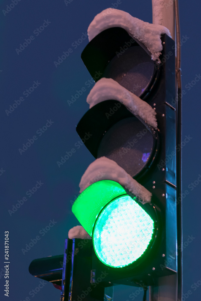 Green light traffic light on a dark background. A closeup photo of ...