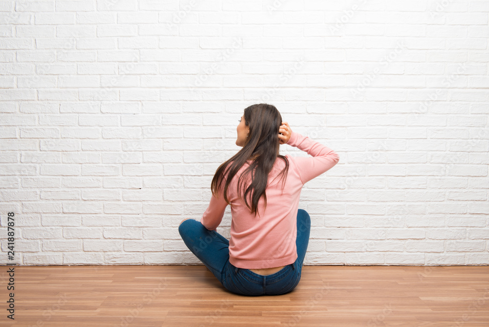 Teenager girl sitting on the floor in a room on back position looking ...