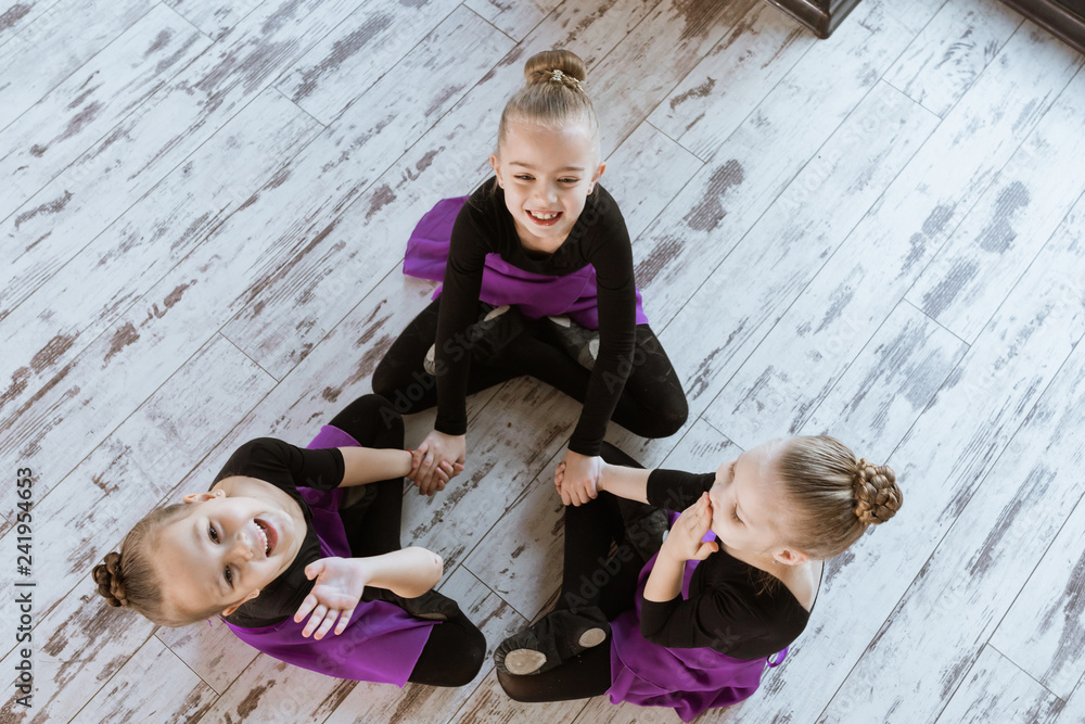 Top view of kids in black uniform and skirt sitting on floor at dance ...