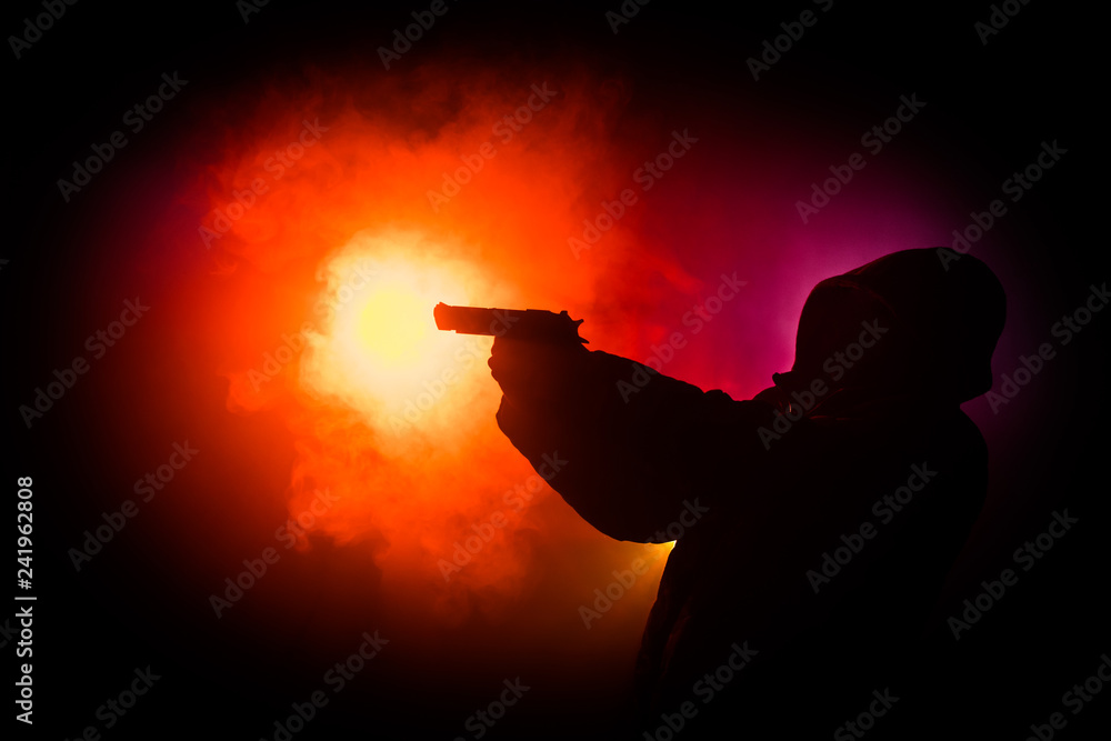 Silhouette of man with assault rifle ready to attack on dark toned ...