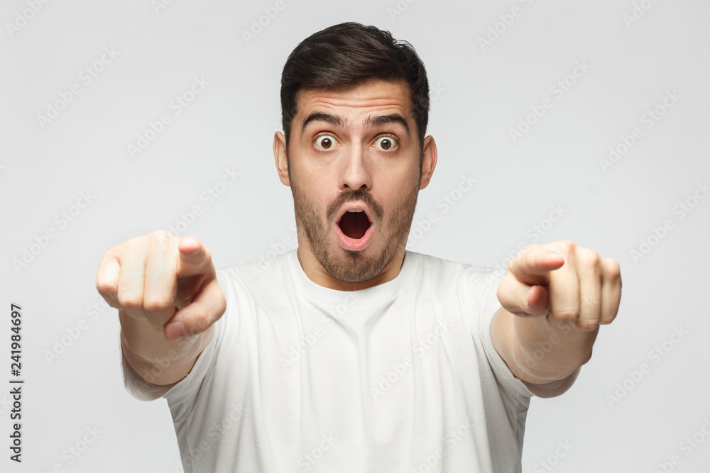 European male pointing at camera with both hands with amazed and ...
