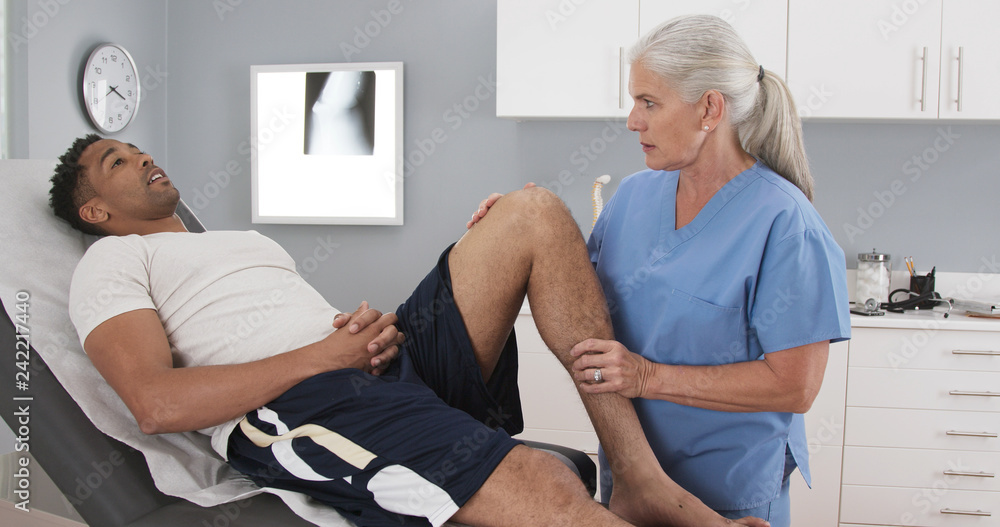 Foto de Male millennial black patient at clinic with injured knee ...