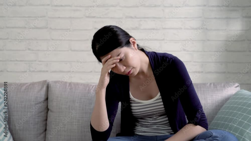 Sad depressed woman crossed legs sitting on couch at home feeling ...