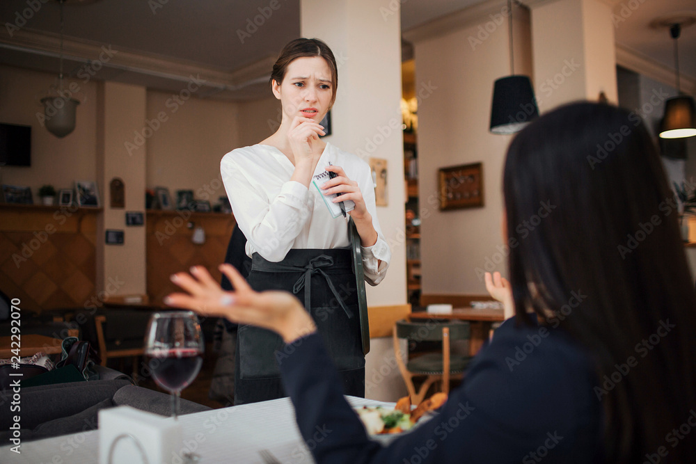 Female customer complain to waitress. She hold hands aside. Waitress ...