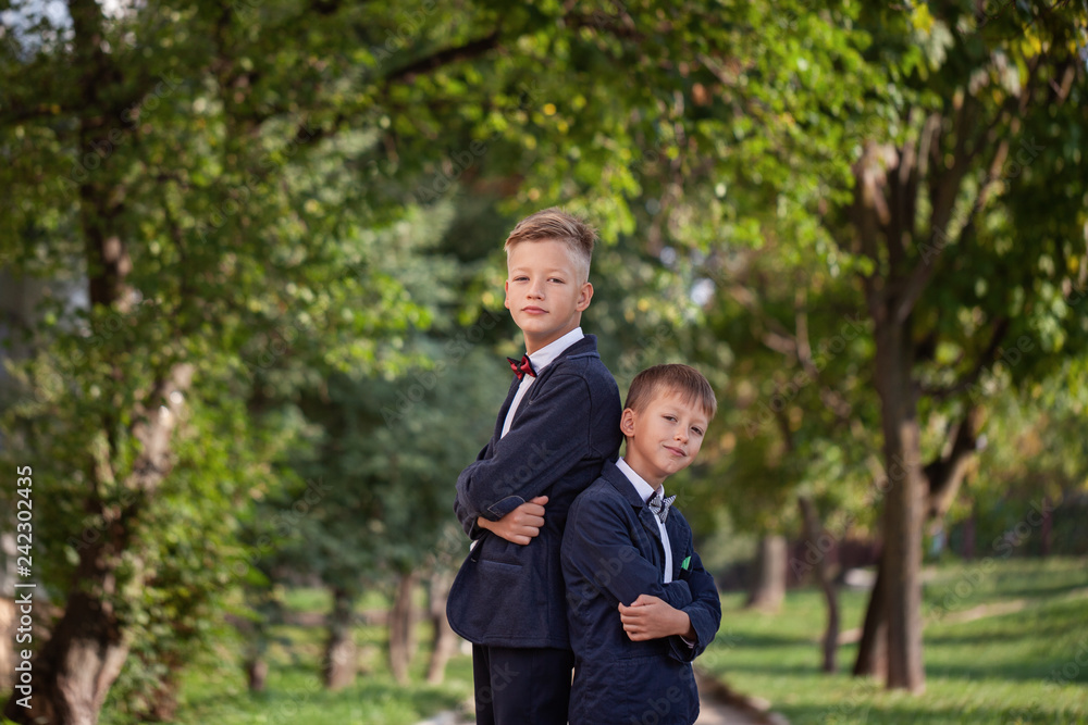 Happy two boys standing back to back on nature background in summer day ...