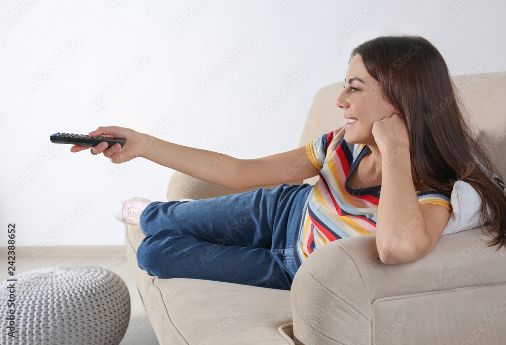 Beautiful young woman watching TV on sofa at home Stock Photo | Adobe Stock