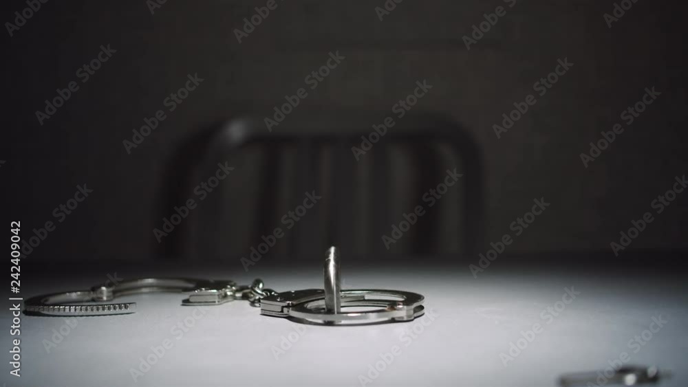 Close-up shot that slowly dollies in on a pair of handcuffs in an ...