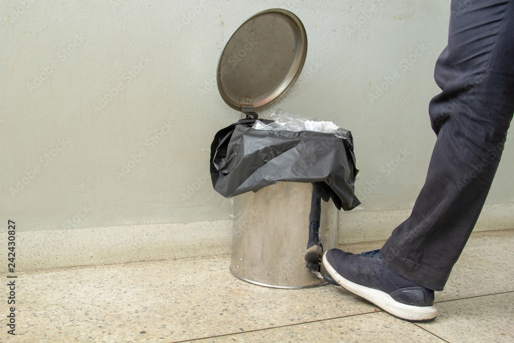 Man's foot open garbage bin on gray background and putting smartphone ...