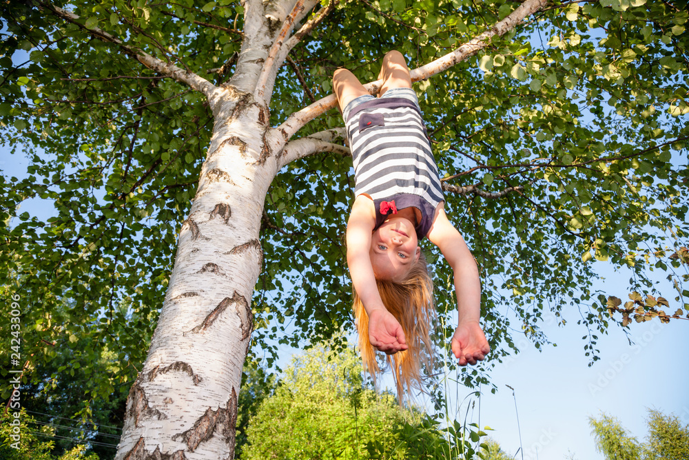 Happy girl hanging from a tree in a summer park Stock Photo | Adobe Stock