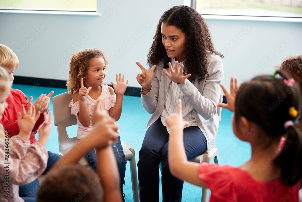 Elevated view of infant school children sitting on chairs in a circle ...