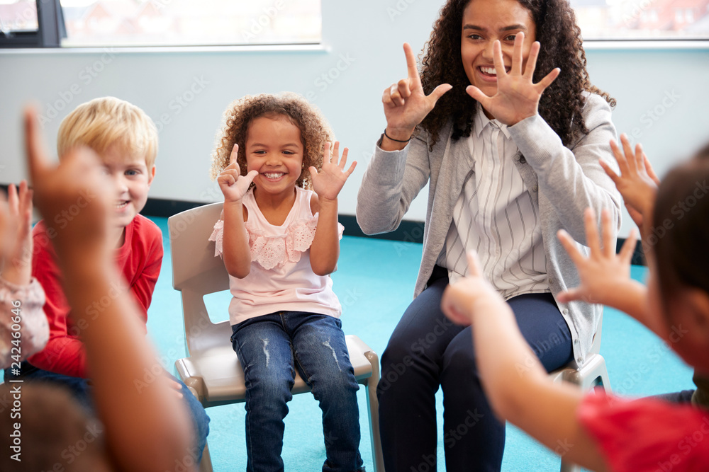 Front view of infant school children sitting on chairs in a circle in ...