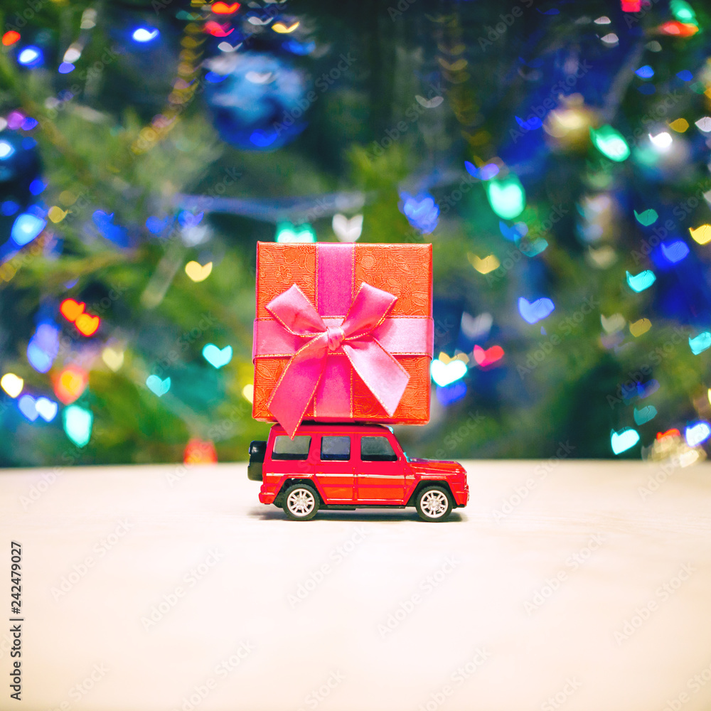 Red car, gift box with a red bow on an abstract background blurred ...