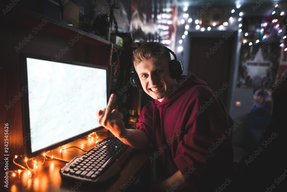 Portrait of an evil gamer gamer plays a game on a computer, looks at ...