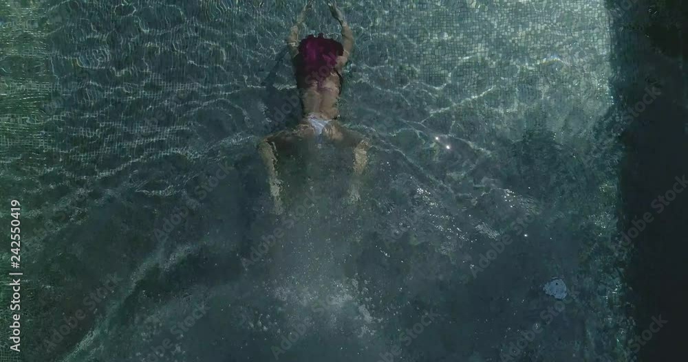 AERIAL CLOSE UP TOP DOWN: Young woman on summer vacation jumping head ...