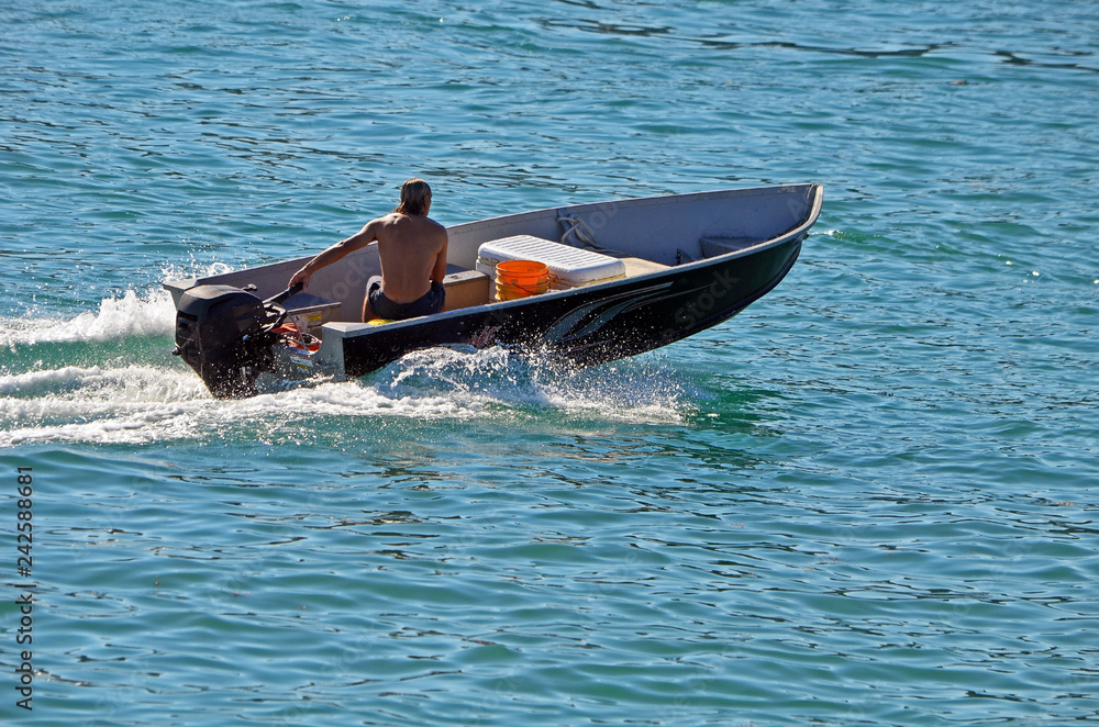 Small open fishing boat ;powered by a single outboard engine speeding ...
