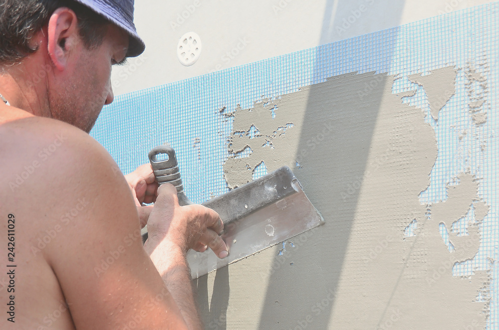 Fifty years old manual worker with wall plastering tools renovating ...