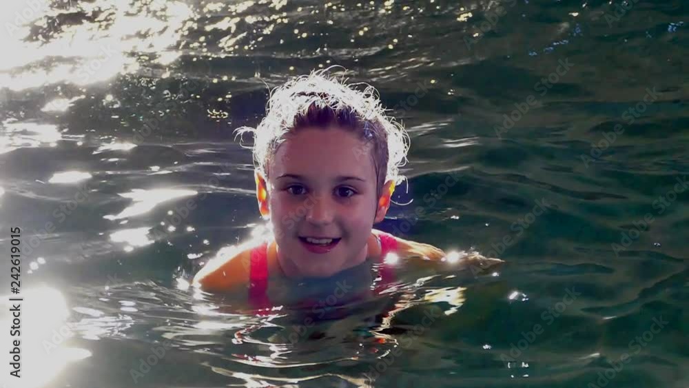 The girl swims in the pool. Splashing water and having fun. In the ...