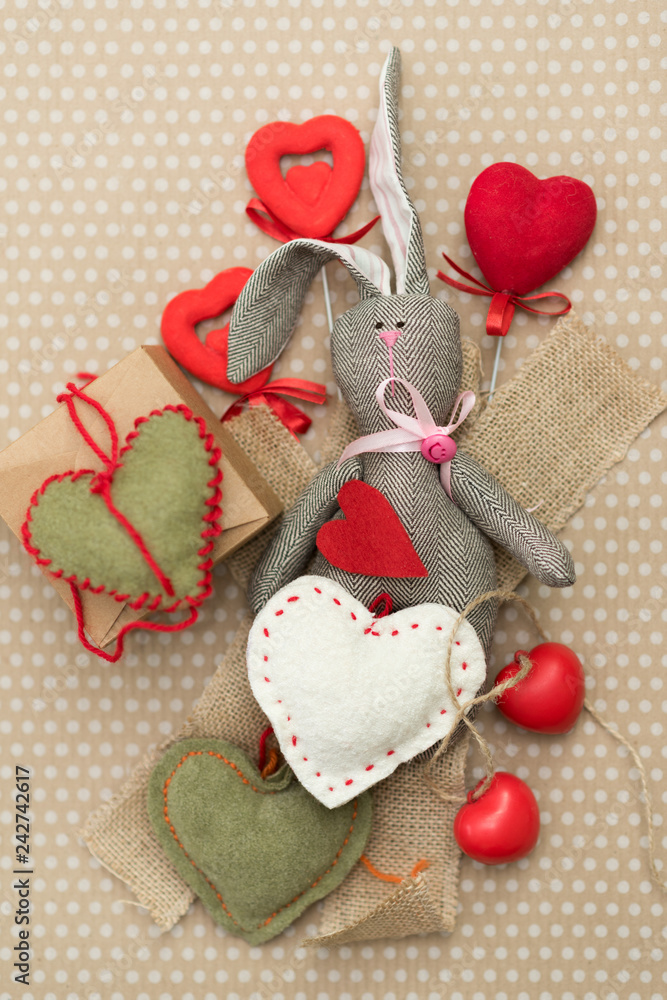 Rabbit handmade with red and white hearts lying on cardboard background ...