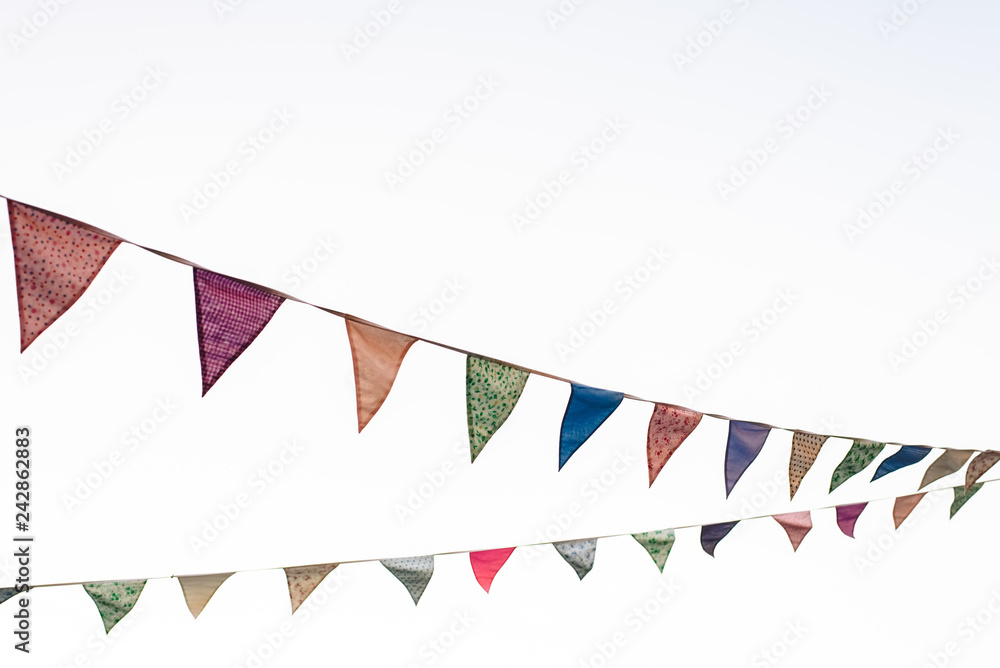 Pennants with blue sky background and pale colors hanging on a rope ...