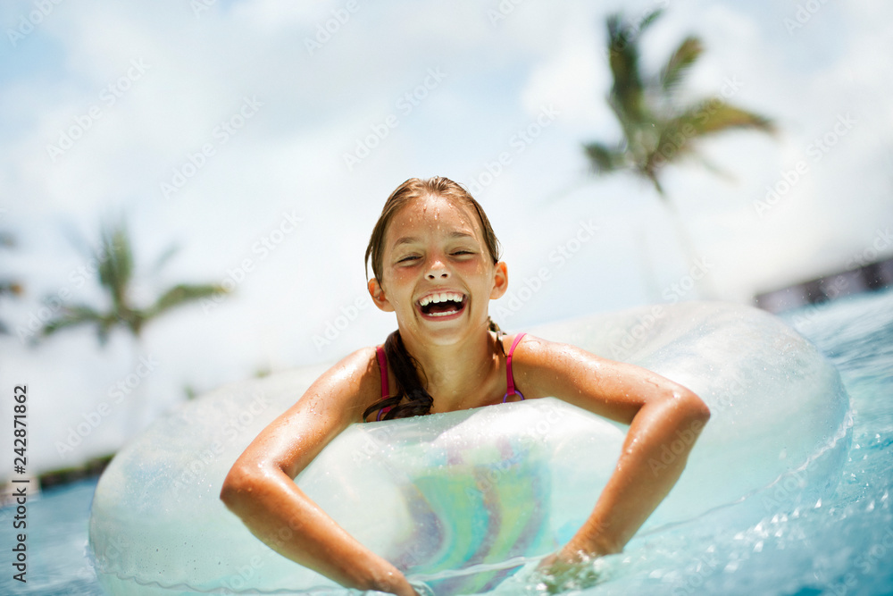 Portrait of a laughing girl floating in an inflatable ring in a ...