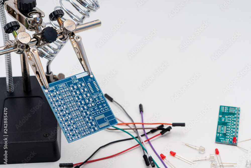 Blue circuit board in soldering helping hands (third hand or auxiliary ...