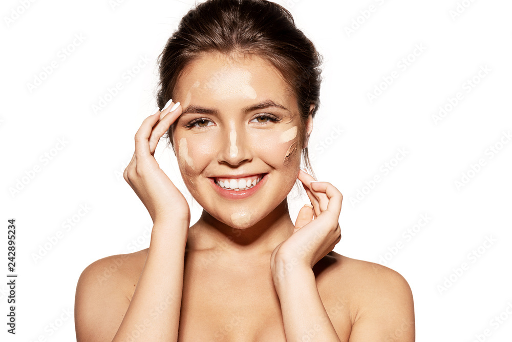 Portrait of happy laughing girl making natural make-up using tonal ...