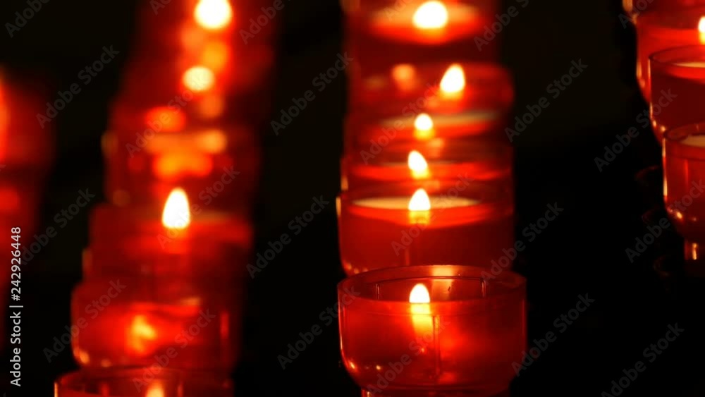 Row of christian prayer red round votive candles burn in the dark ...