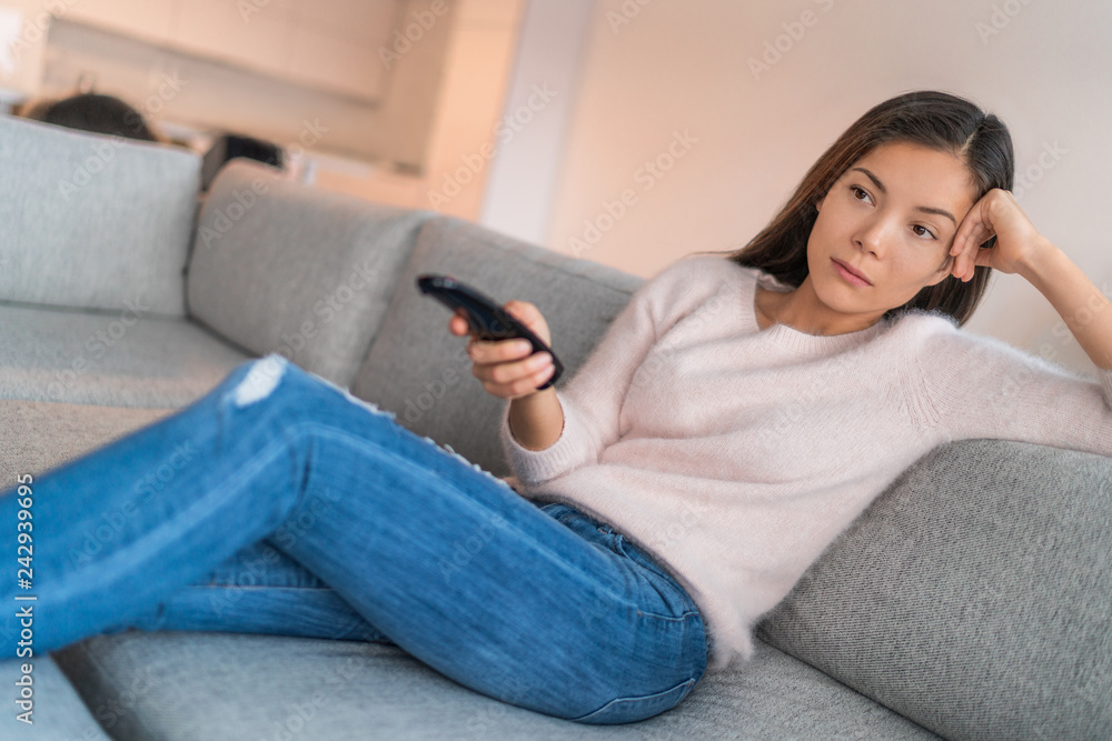 Bored Woman Watching Tv Alone In Apartment Sitting On Sofa Holding