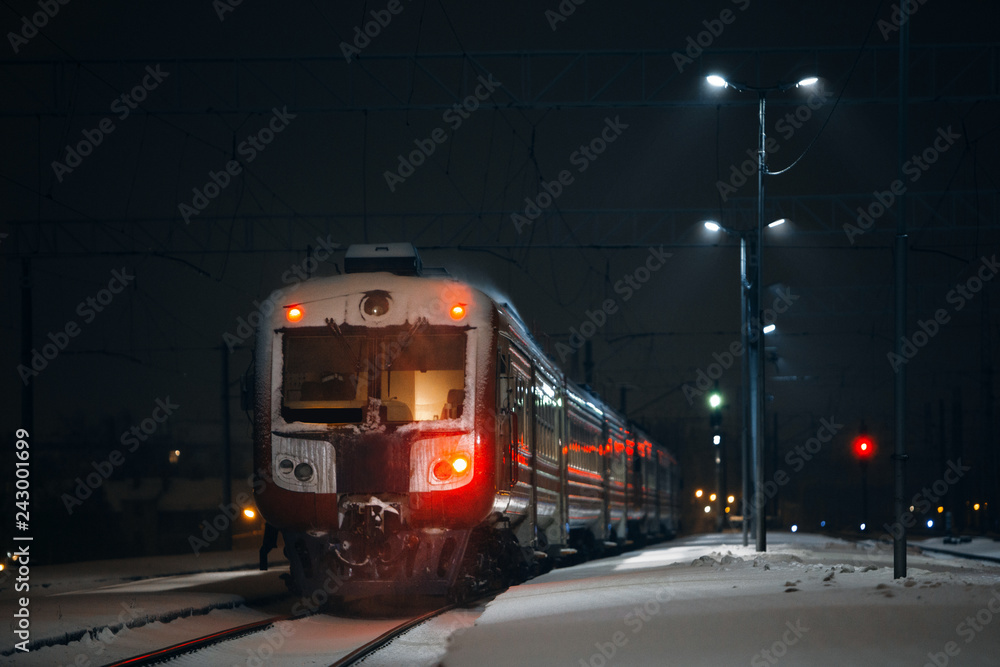 Train on railroad station during snowing at night. Train at the empty ...