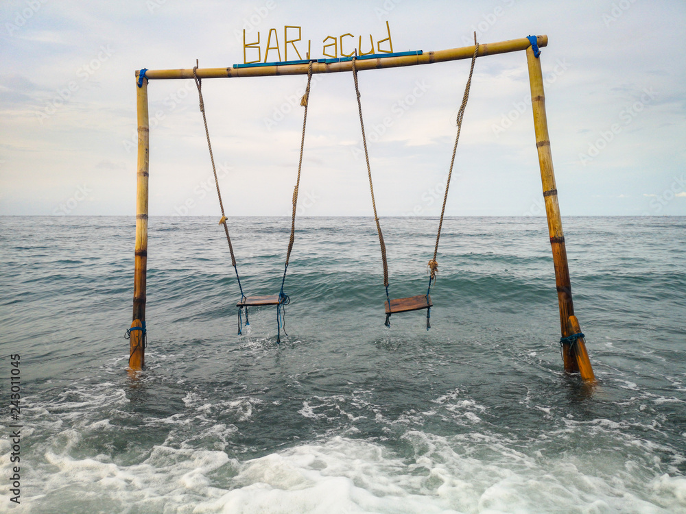 Double swing in the ocean at the beach in Amed village in Bali ...