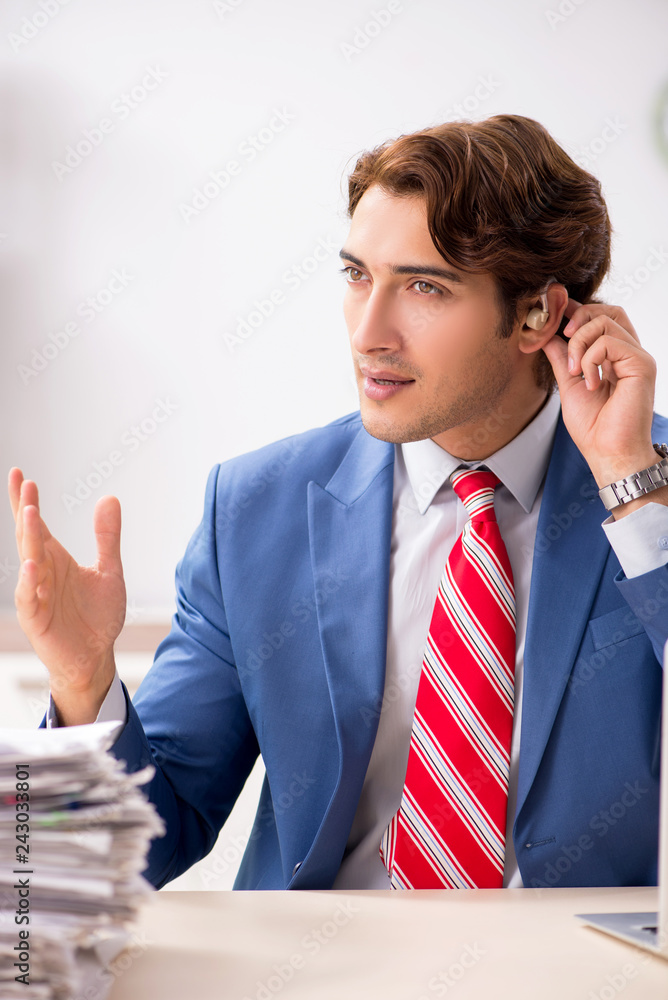 Deaf employee using hearing aid in office Stock Photo | Adobe Stock