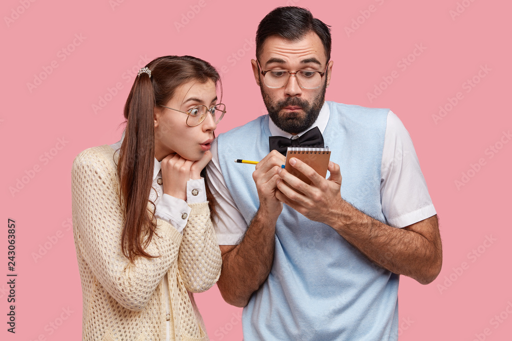 Astonished intelligent classmates with comic looks, stare at notepad ...