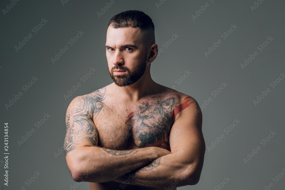 serious strong man with crossed arms on the isolated grey background ...