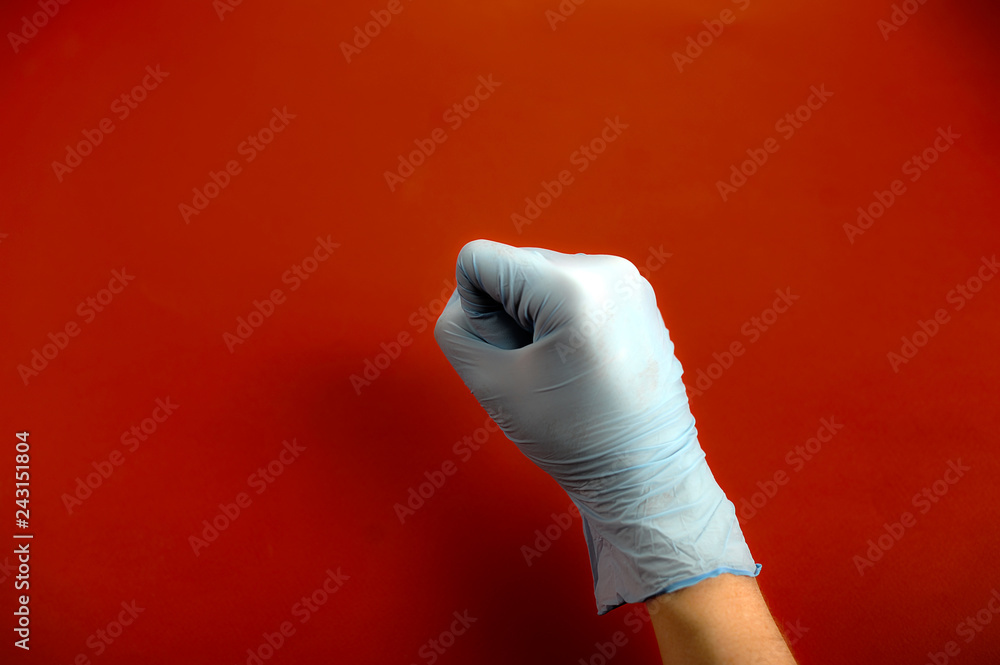Hand in medical latex glove. Hand clenched into a fist. Red background ...