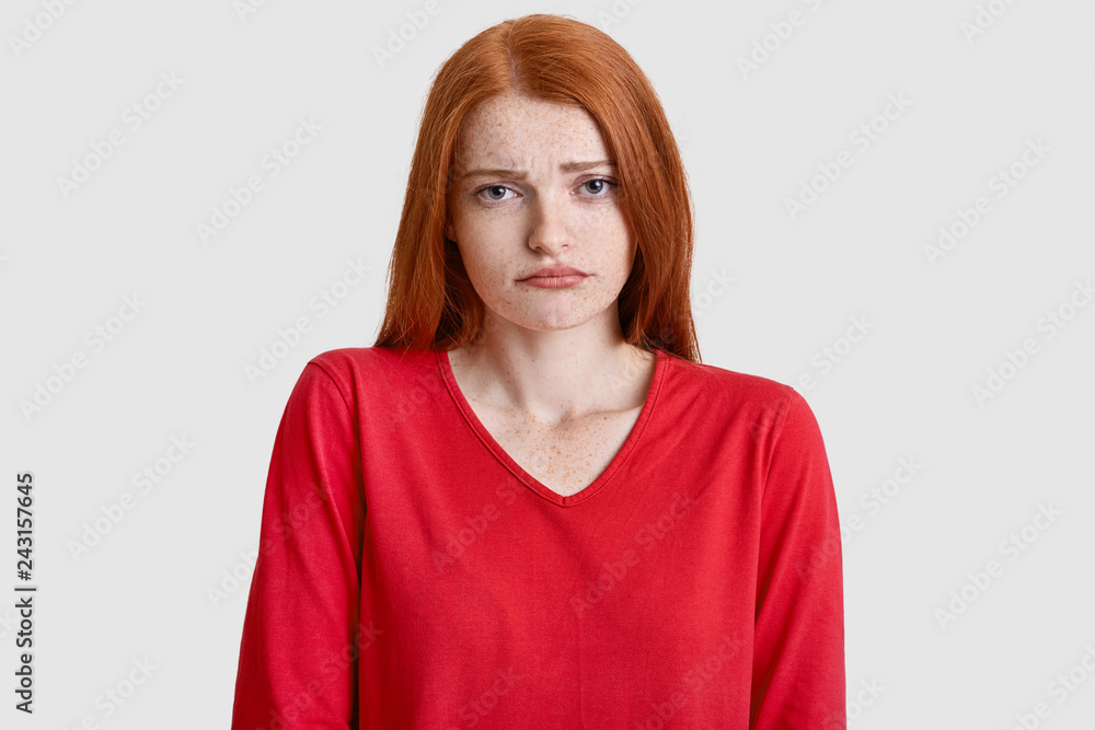 Foto de Displeased ginger lady frowns face, has freckled skin, wears ...
