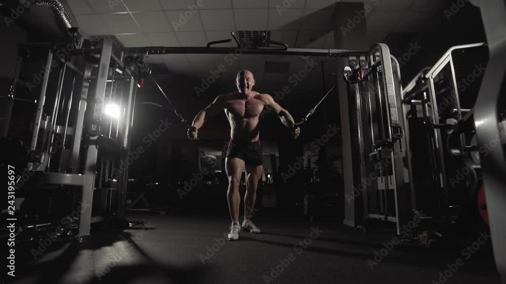 Male bodybuilder training chest muscles exercise using cable cross over ...