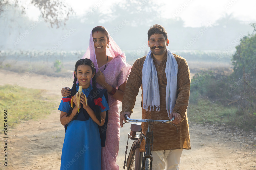 Happy rural family consisting of man, woman and a school going girl ...